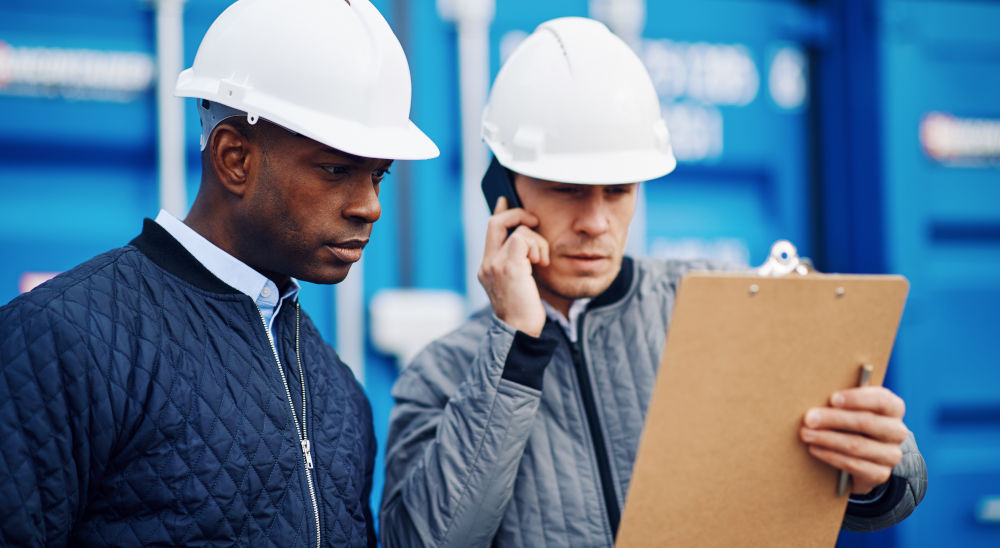 Engineers tracking inventory together in a commercial freight shipyard ...